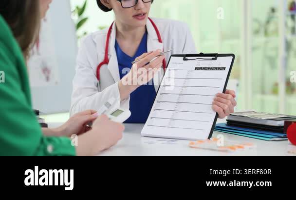 Female doctor explains medical form during clinic consultation ...