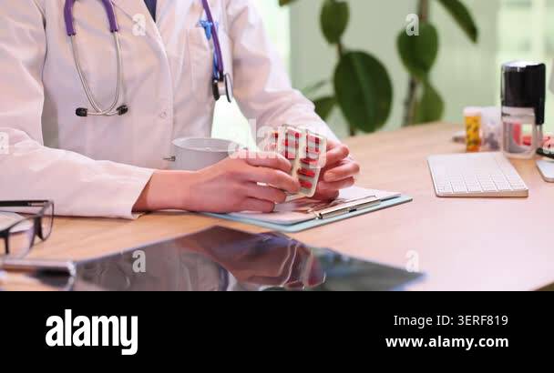 Doctor hands hold pills blisters over clipboard in clinic office ...