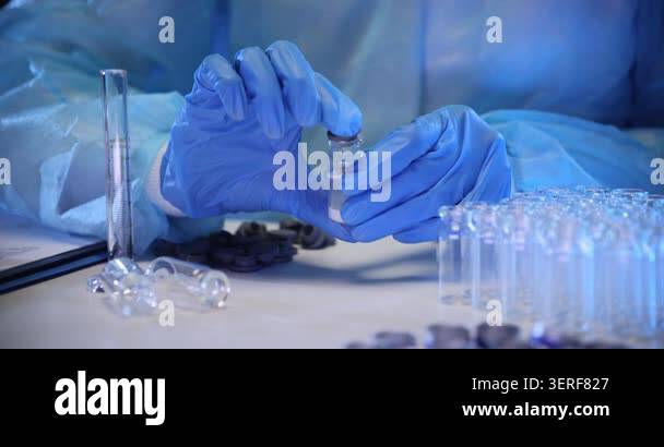 Laboratory worker closes lid of transparent bottle filled with ...