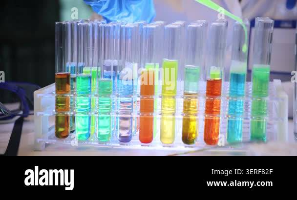 Scientist hand drips reagent into test tubes with color fluids in ...