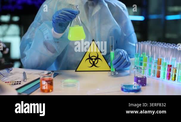 Diligent lab worker studies vivid chemical liquids in glass test tubes ...