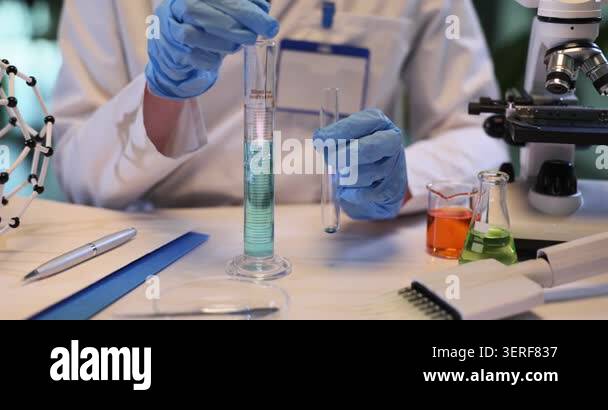 Woman scientist takes blue liquid with pipette from beaker in chemical ...