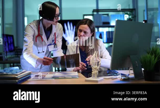 Female doctor shows x-ray image of patient wrist to colleague in clinic ...