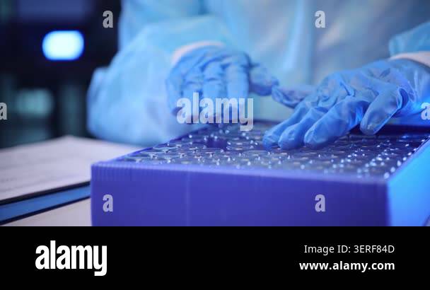 Laboratory worker removes small transparent bottles from storage box ...