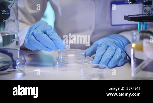 Woman scientist pours metallic liquid onto glass podium in chemical lab ...