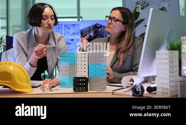 Architectural designers examine detailed models of multi-story ...