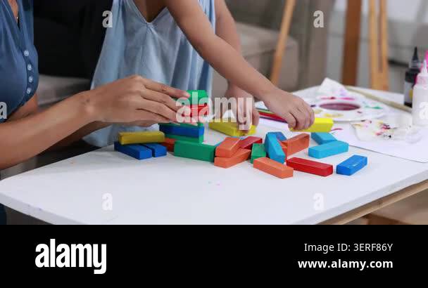 Adult and child playing with colorful wooden blocks at a table during ...