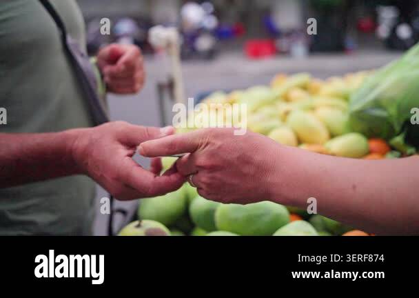 Close view of two peoples hands near a pile of ripe green and yellow ...