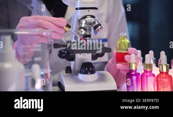 Assistant hand drips serum onto microscope slide in medical lab. Female ...