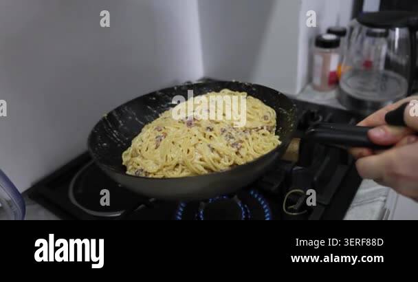 Cook mixes flavorful spaghetti with crispy bacon and creamy sauce by ...