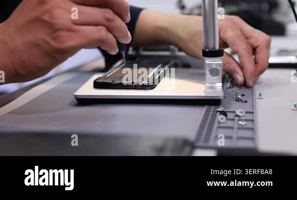 Close-up of a technician repairing a smartphone with a small ...