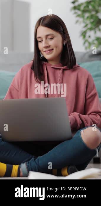 Woman sits on floor with a laptop, studying and enjoying her time in a ...