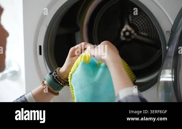 Female hands place yellow and blue mesh laundry bag into open front ...
