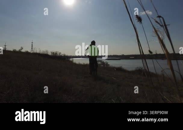 man in a neon-yellow jacket rides a loaded mountain bike down a dry ...