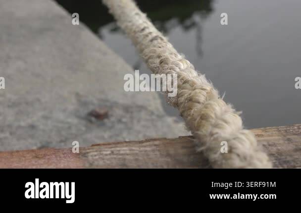 Thick braided mooring rope tied from a concrete pier to a green ...