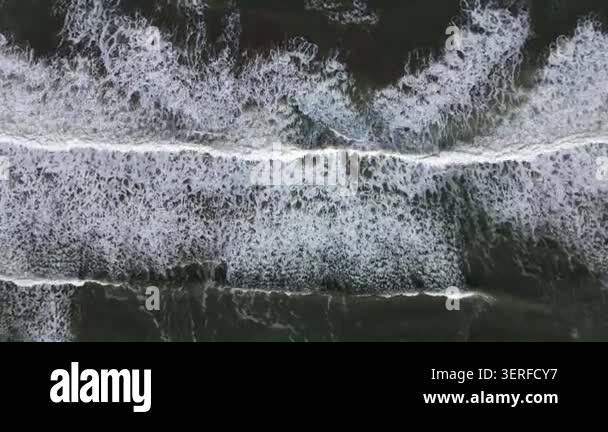 Aerial view of ocean waves crashing on the shore, showing the dynamic ...