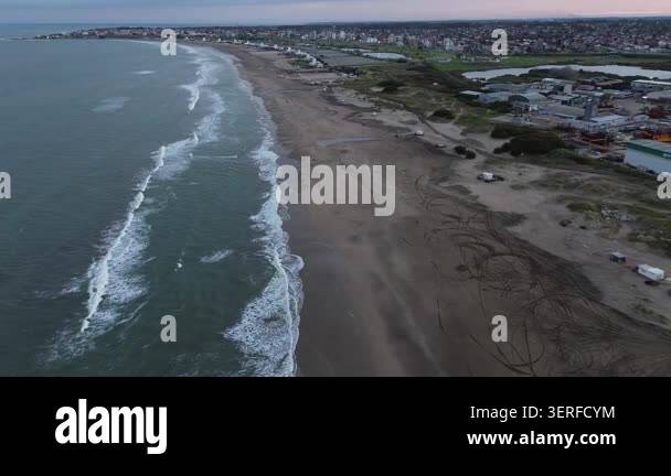 Aerial drone footage captures a wide view of a sandy beach with gentle ...
