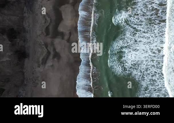 Aerial view of ocean waves crashing on a sandy beach, captured in a ...