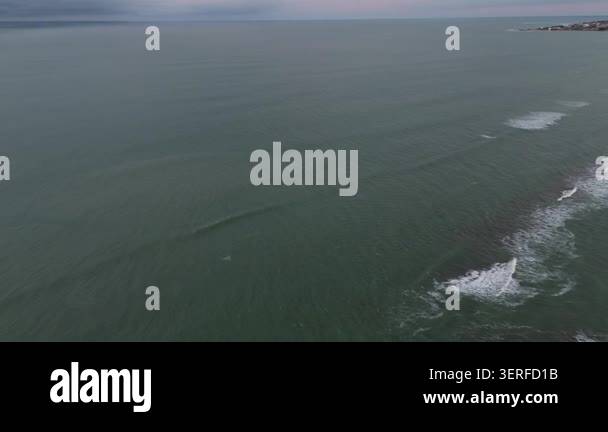 Aerial drone footage captures gentle waves rolling onto a sandy beach ...