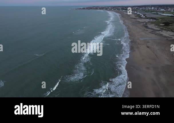 Aerial drone footage captures a wide view of a sandy beach with gentle ...