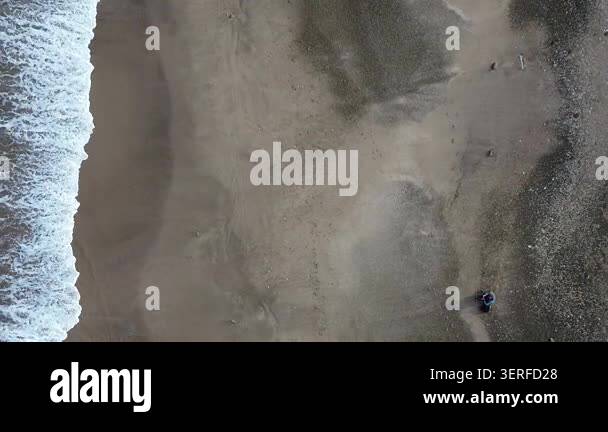 Aerial view of gentle waves washing onto a sandy beach with a lone ...