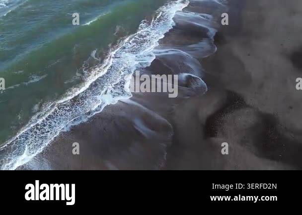 Aerial view of ocean waves gently washing onto a sandy beach ...