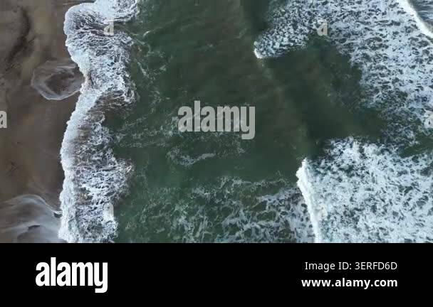 Aerial view of ocean waves crashing on a sandy beach, showcasing the ...