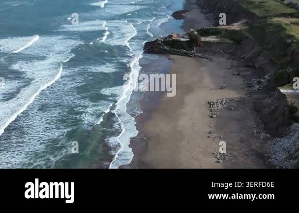 Aerial drone footage captures the vast ocean waves crashing onto a ...