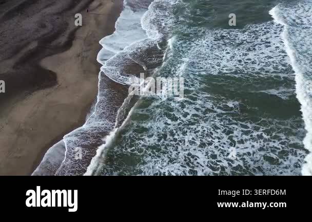 Aerial view of ocean waves crashing on a sandy beach, showcasing the ...