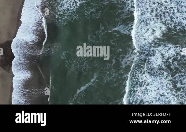 Aerial view of ocean waves crashing on a sandy beach, showcasing the ...