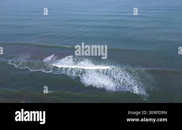 Aerial view of ocean waves breaking on the shore, showing white foam ...