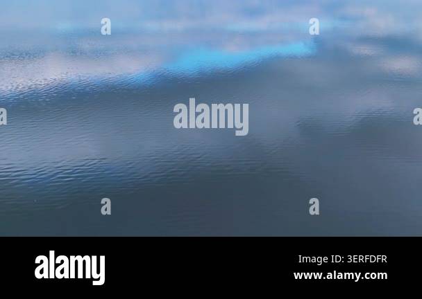 Still lake water reflecting clouds in abstract blue tones. Close aerial ...