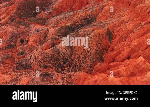 Elevated view of eroded red hillside with scattered desert scrub, Spain ...