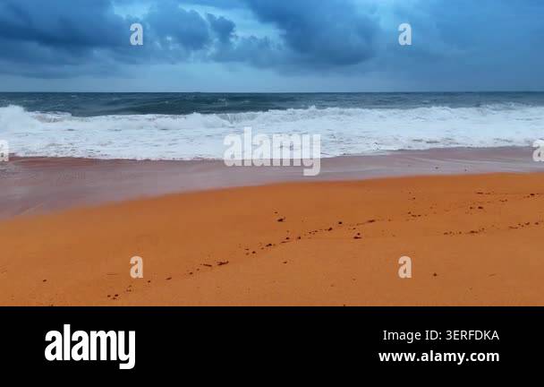 Overcast sky above orange sand beach and rolling surf, Panama. Wide ...