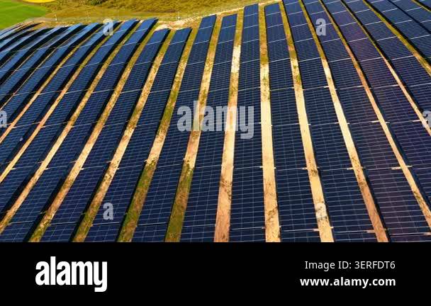 Close aerial view of parallel solar panel rows on dry ground. Low drone ...
