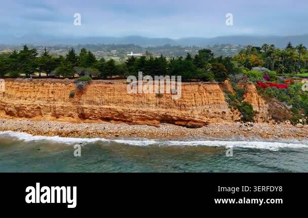Sandy cliffs on the shore with beautiful trees growing on. Waves roll ...