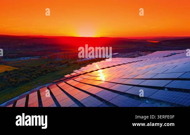 Aerial view of photovoltaic power station at orange sunset. Rows of ...
