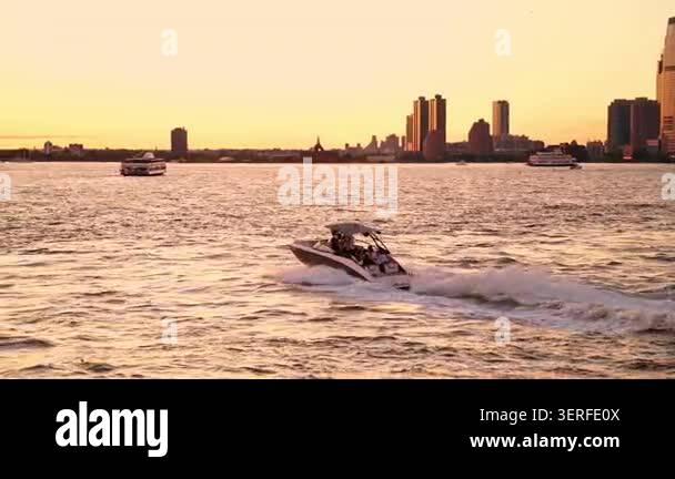 New York, USA, 8 May 2026: Golden sunset over a motorboat on the river ...