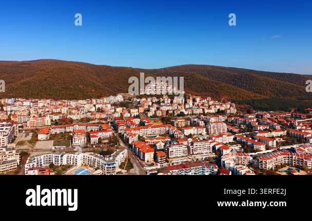 Residential hillside town with red rooftops and forested mountain ...