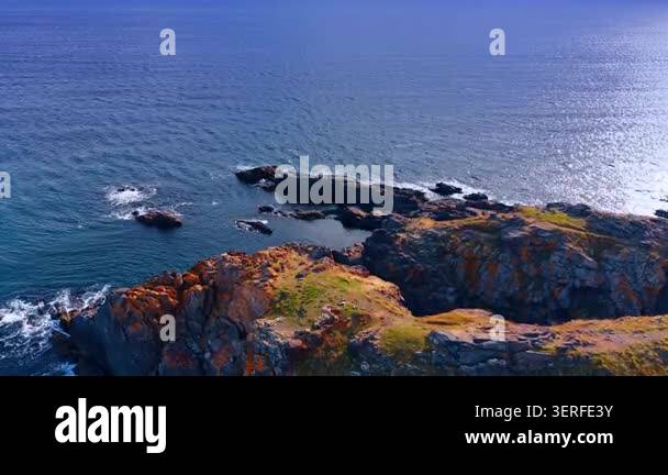 Rocky headland jutting into calm blue sea at golden hour. Elevated ...