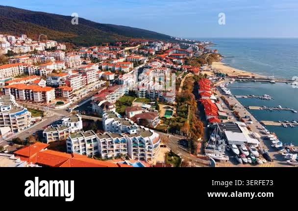 Elevated view of coastal resort district with marina and forested hills ...