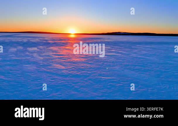 Vivid sunset glow on snow covered frozen lake, Lapland. Wide aerial ...