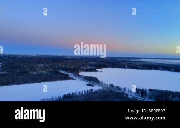 Aerial view of highway through snowy landscape with moonrise, Lapland ...