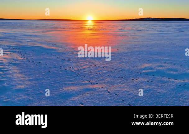 Animal tracks on frozen lake at sunrise, Lapland. Low angle drone view ...