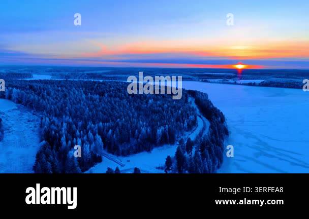 Winter sun touching horizon over frozen river and forest, Lapland ...