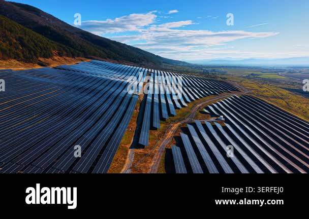 Diagonal rows of solar panels on autumn hillside with distant valley ...