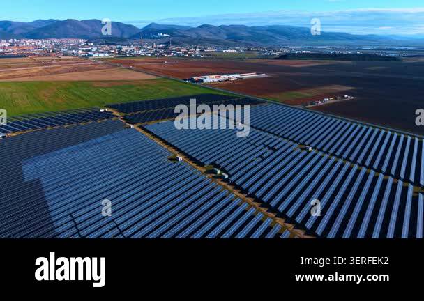 Aerial view of large solar farm near industrial town with mountains ...