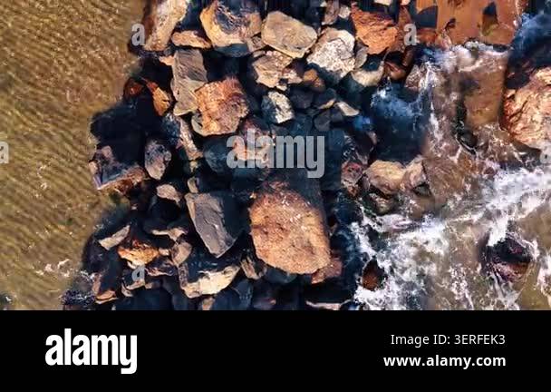 Overhead view of rocky breakwater between calm and turbulent waters ...