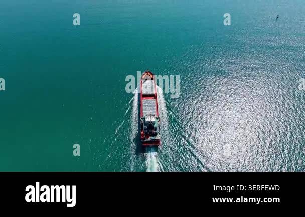 Following a small general cargo vessel sailing across calm turquoise ...