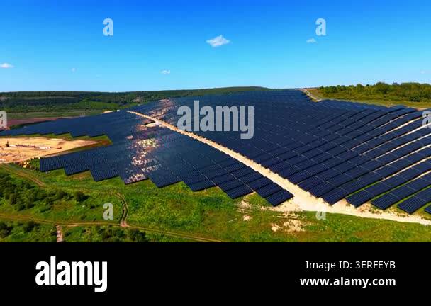 Solar farm under construction with equipment on green hillside ...